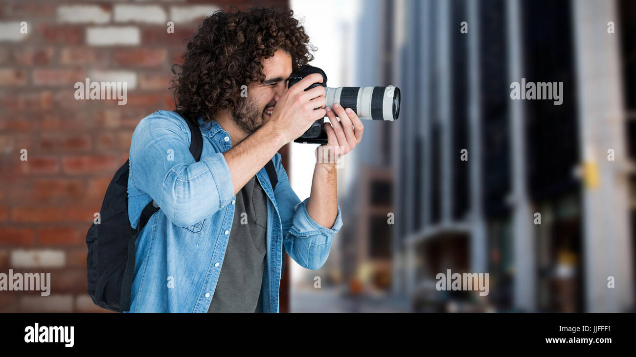 Professional male photographer taking picture against wall of a house ...
