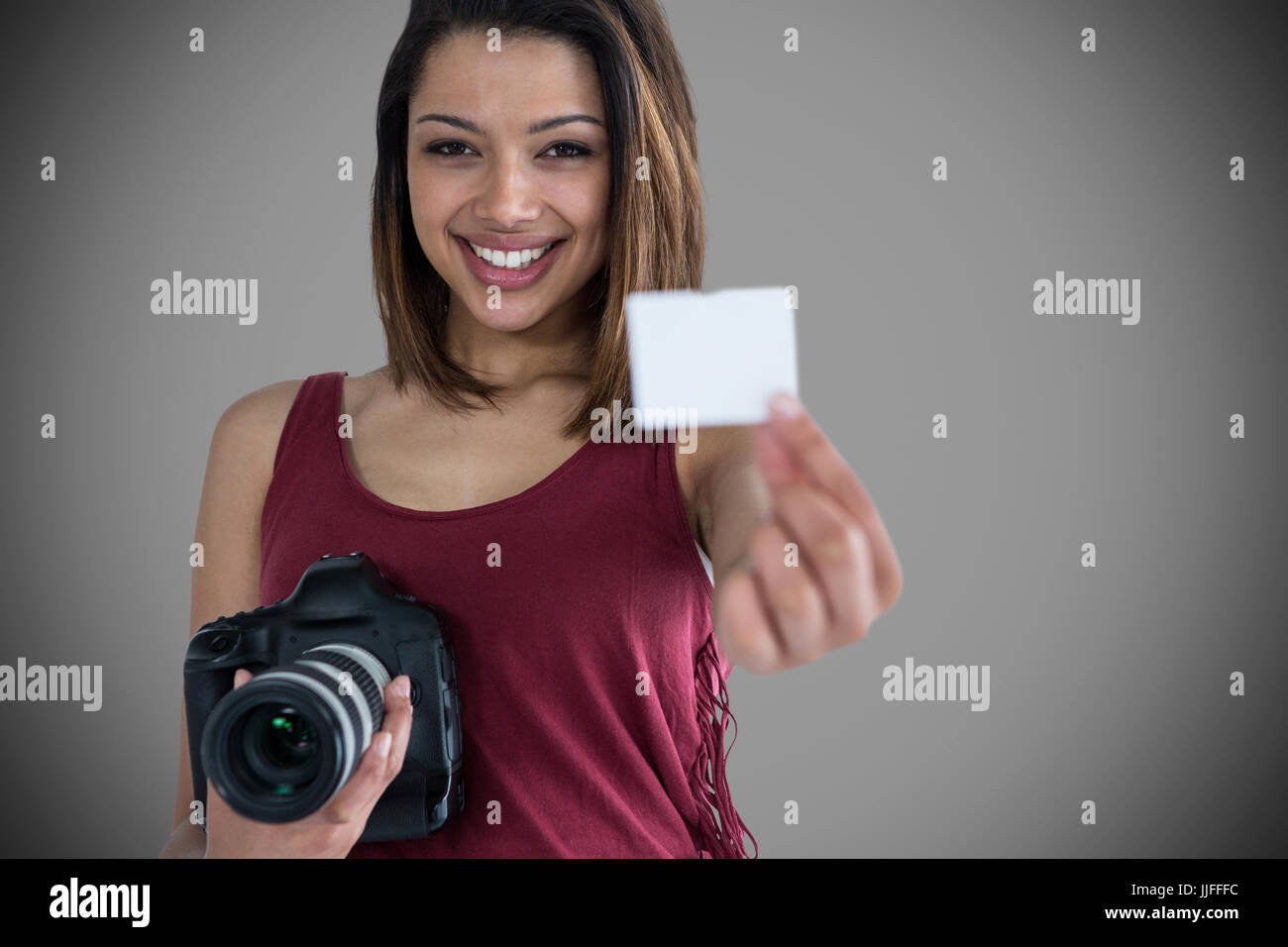 Portrait of happy woman showing identity card while holding camera ...