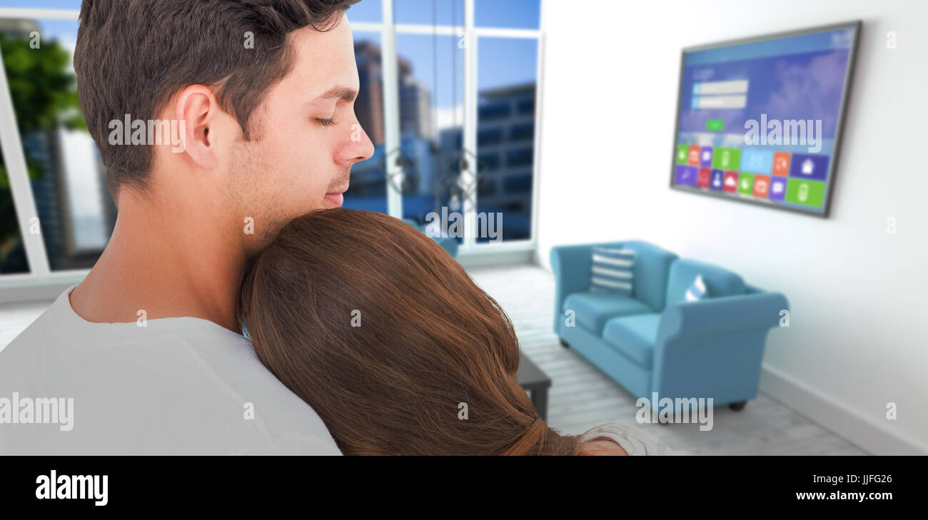 Rear view of couple embracing against blue sofas in living room at ...