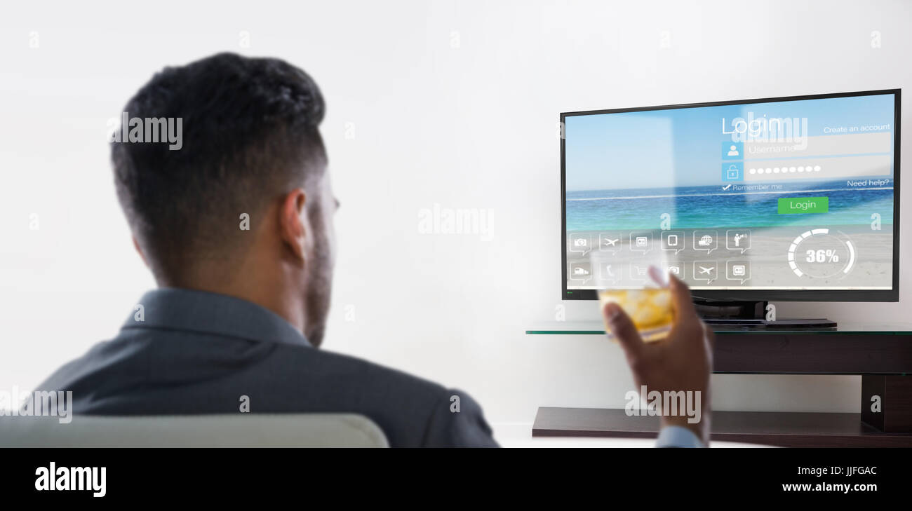Rear view of businessman holding whisky glass against various computer ...