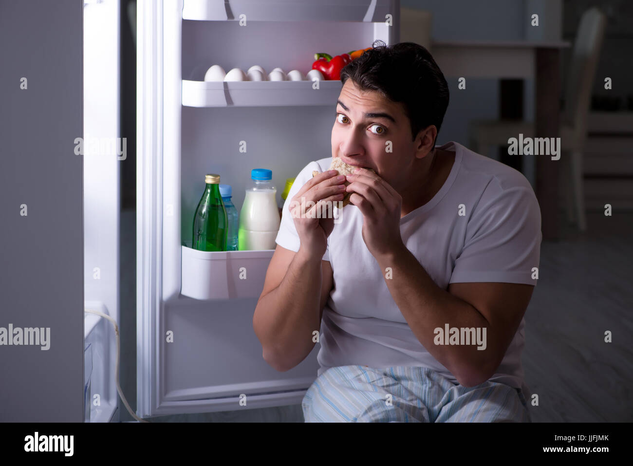 Man at the fridge eating at night Stock Photo - Alamy