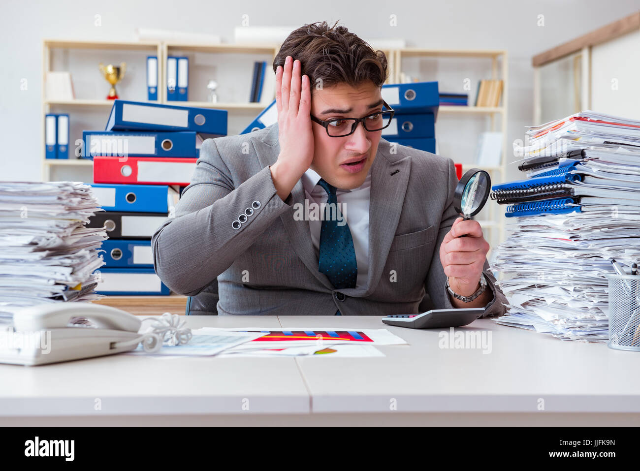 Male businessman with magnifying glass in office Stock Photo - Alamy