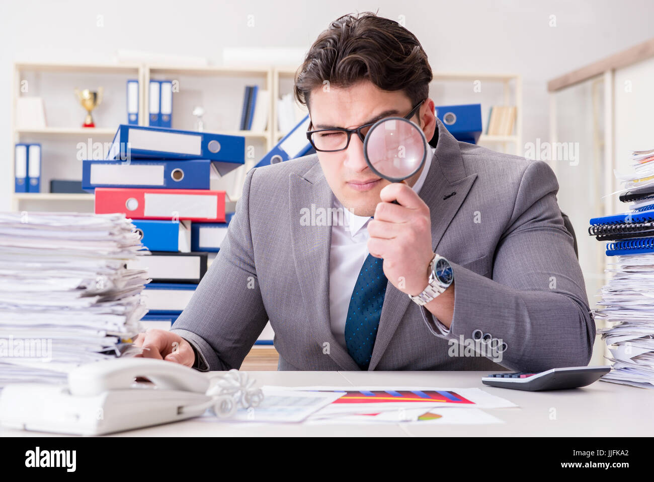 Male businessman with magnifying glass in office Stock Photo - Alamy