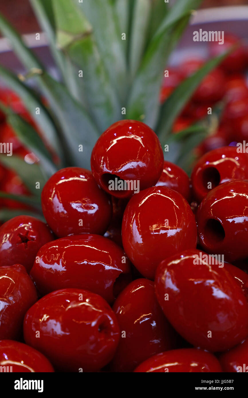 Red pitted glossy Italian Cerignola olives in oil close up over green ...