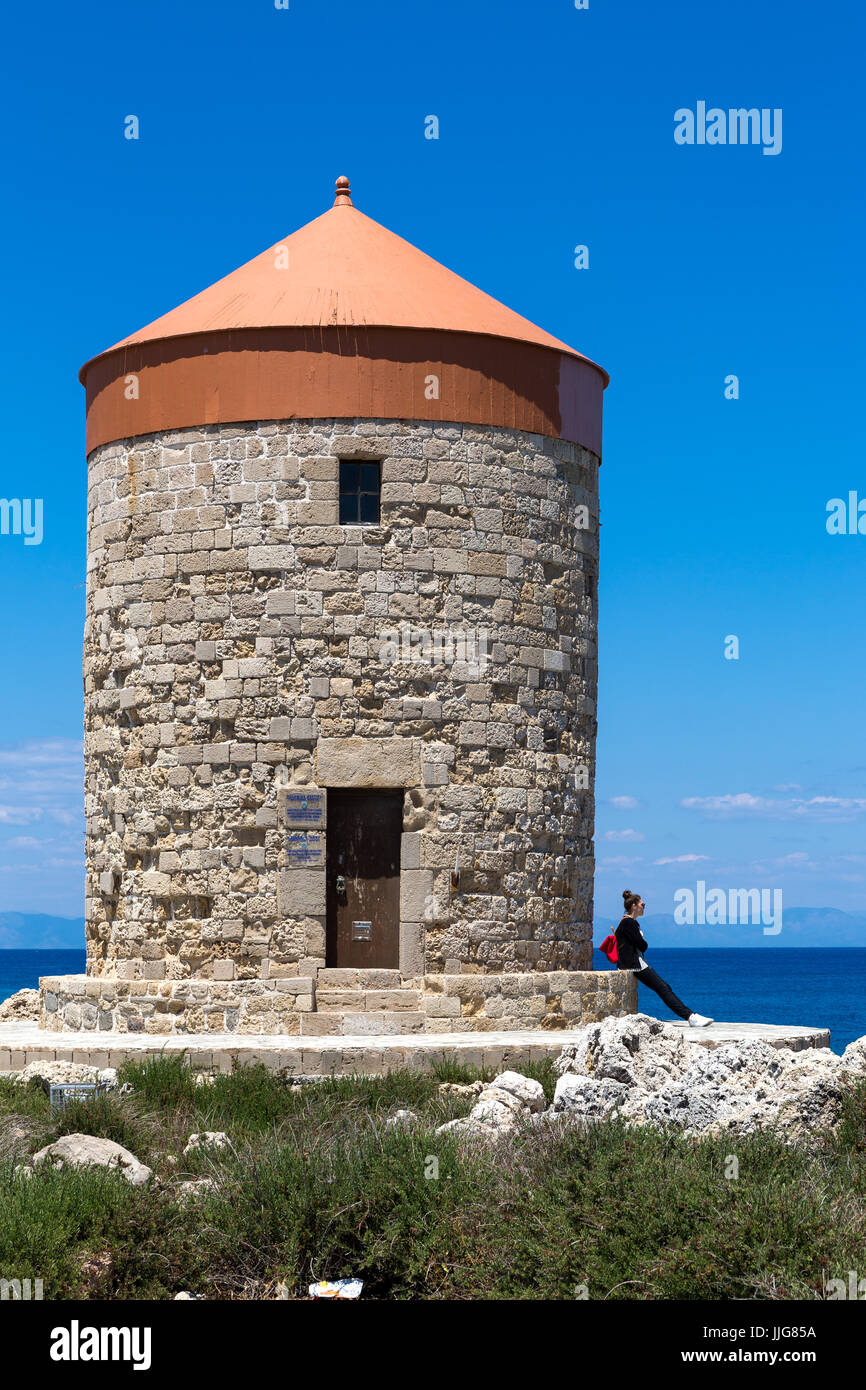 Old windmill at Rhodes harbour with tourist enjoying scenic views ...