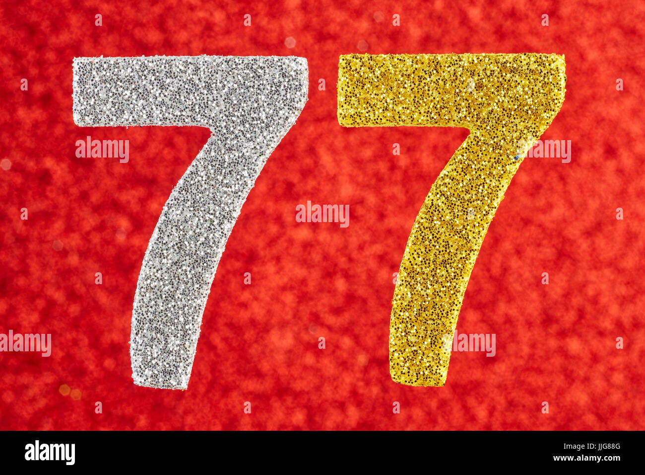 Number seventy-seven yellow silver color over a red background ...