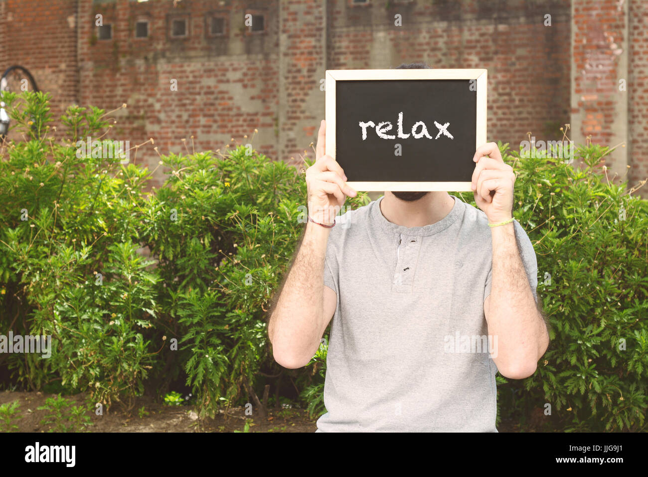 Portrait of handsome young man holding chalkboard with text "relax ...