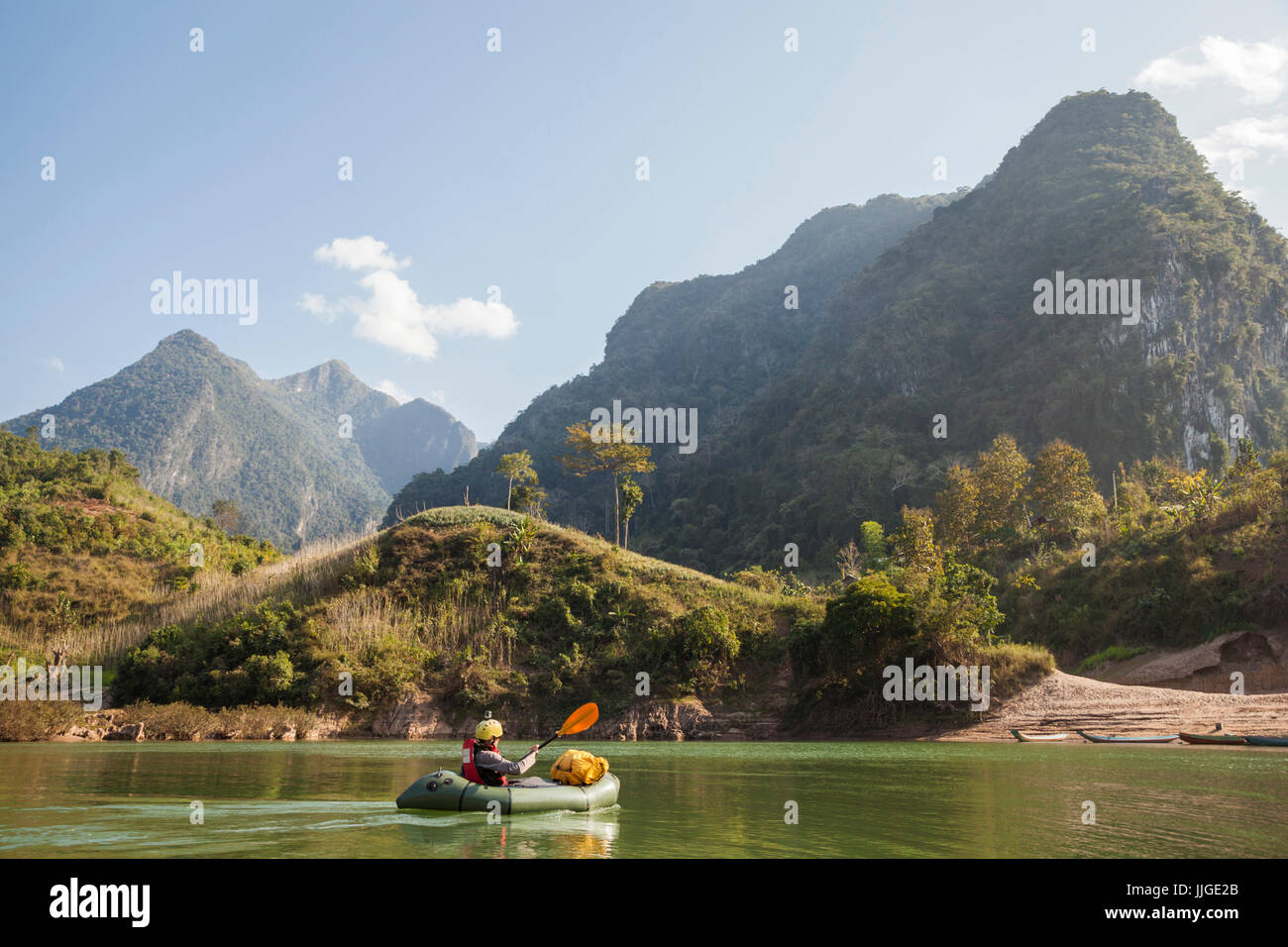 Robert Hahn paddles his packraft under dramatic karst mountains rising ...