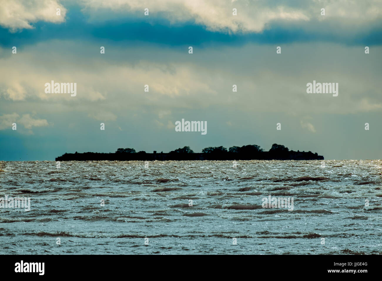 Dark scene with an isolated distant island in the sea and thin light ...