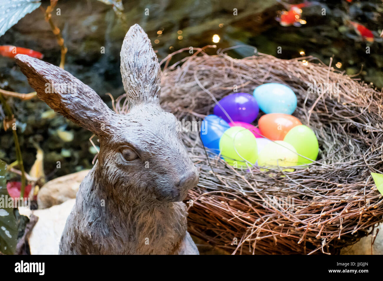 A stone Easter bunny sitting beside a nest of colored eggs Stock Photo ...