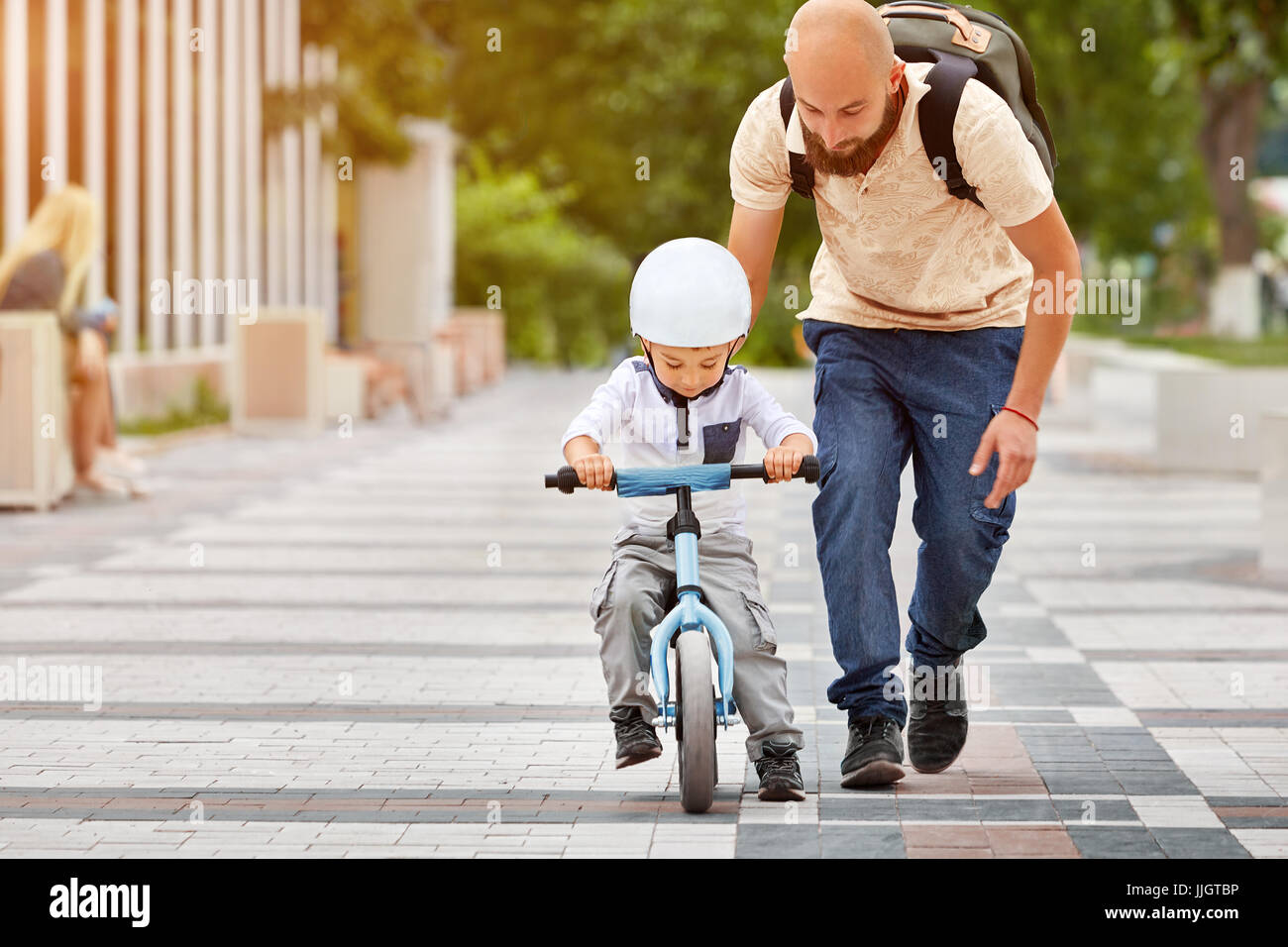 Father help his son ride a bicycle in city park Stock Photo - Alamy