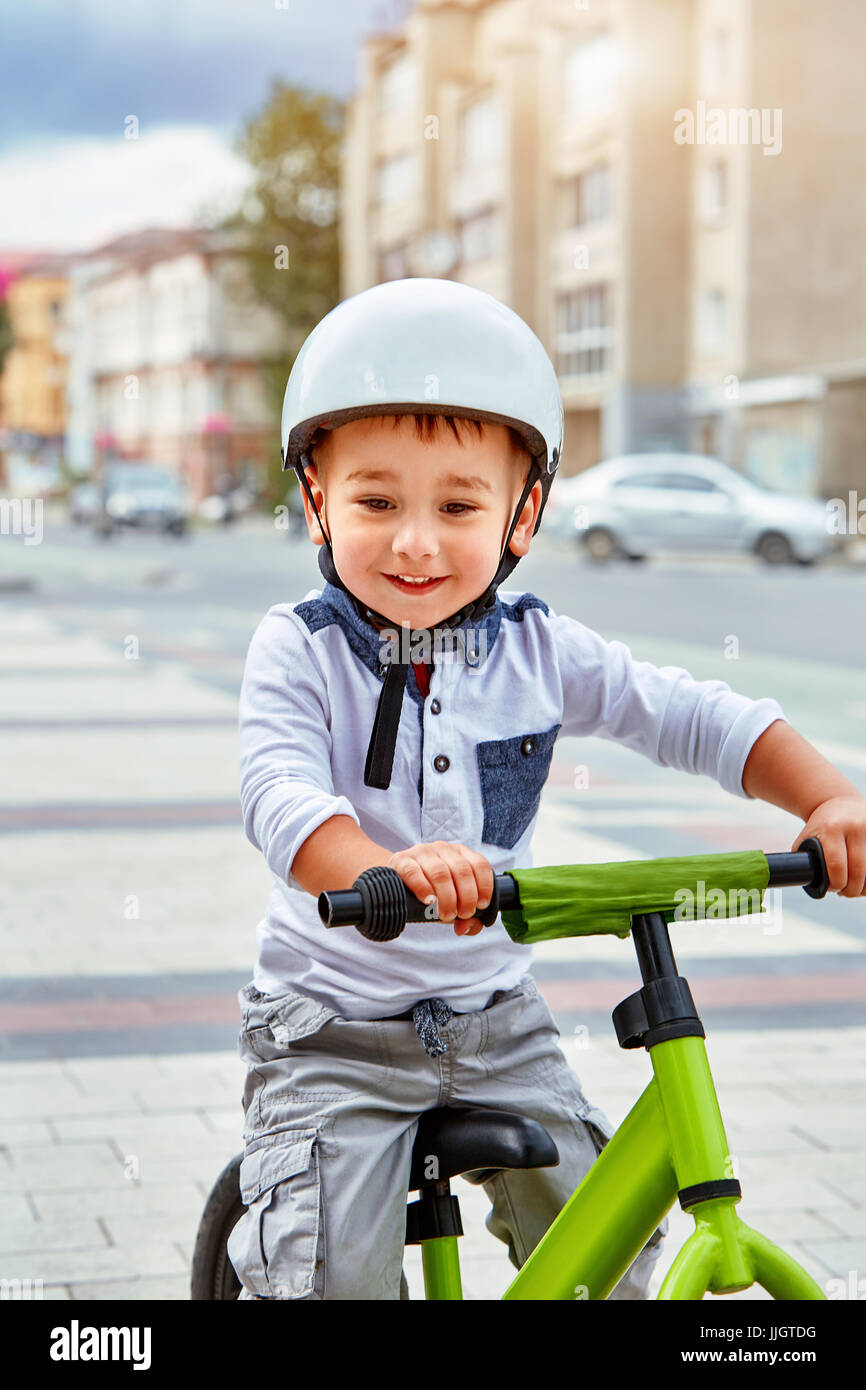 Happy boy in white helmet ride his first bike in city park Stock Photo ...
