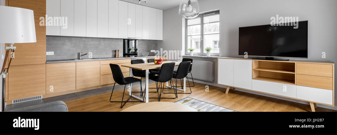 Modern open space kitchen, dining table and big television, panorama ...