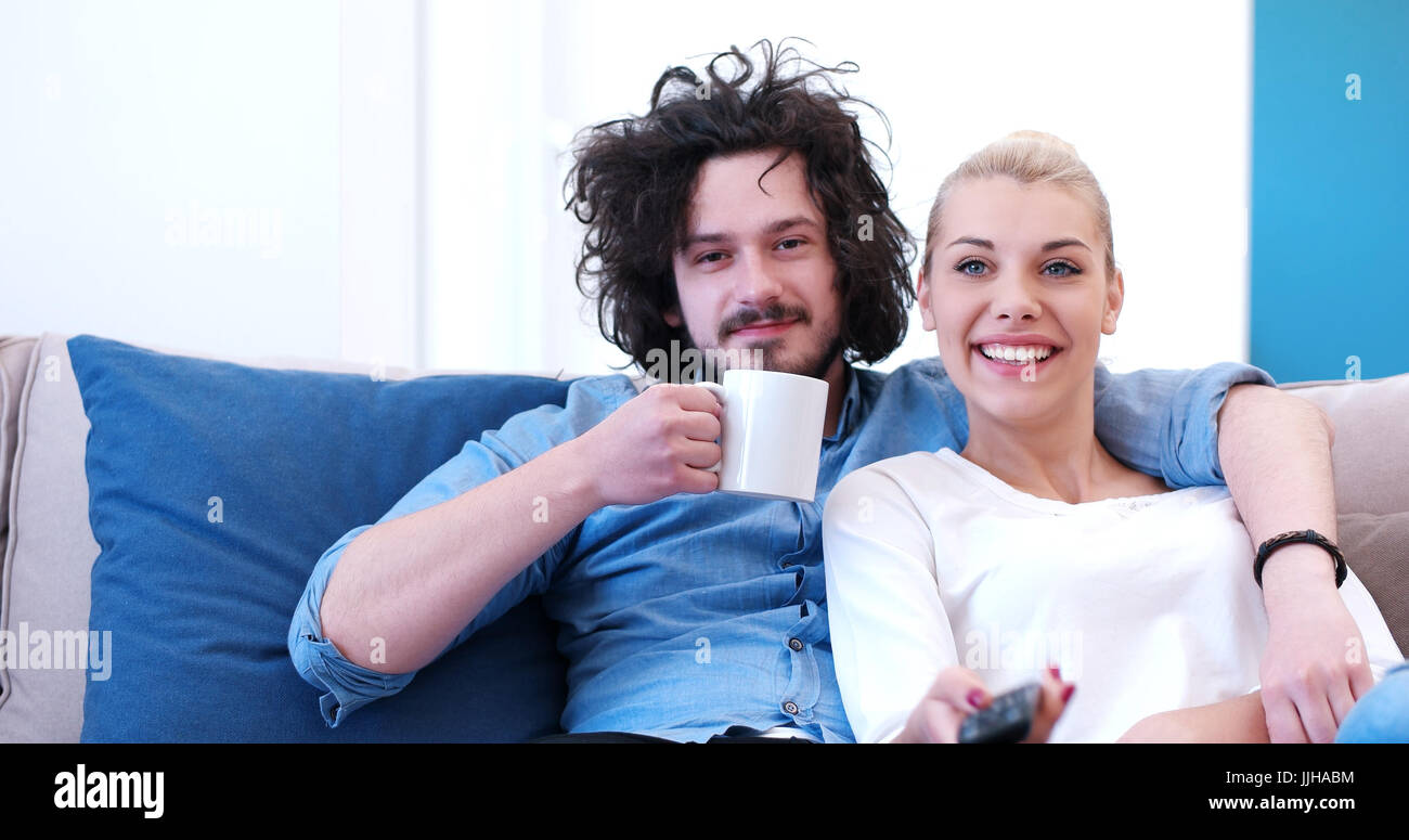 Young couple on the sofa watching television together in their luxury ...