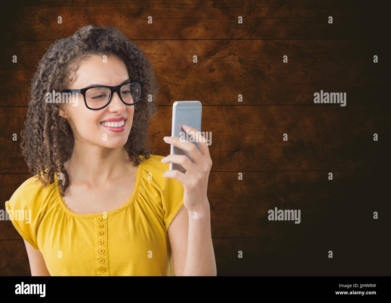Smiling woman texting against wooden background Stock Photo - Alamy