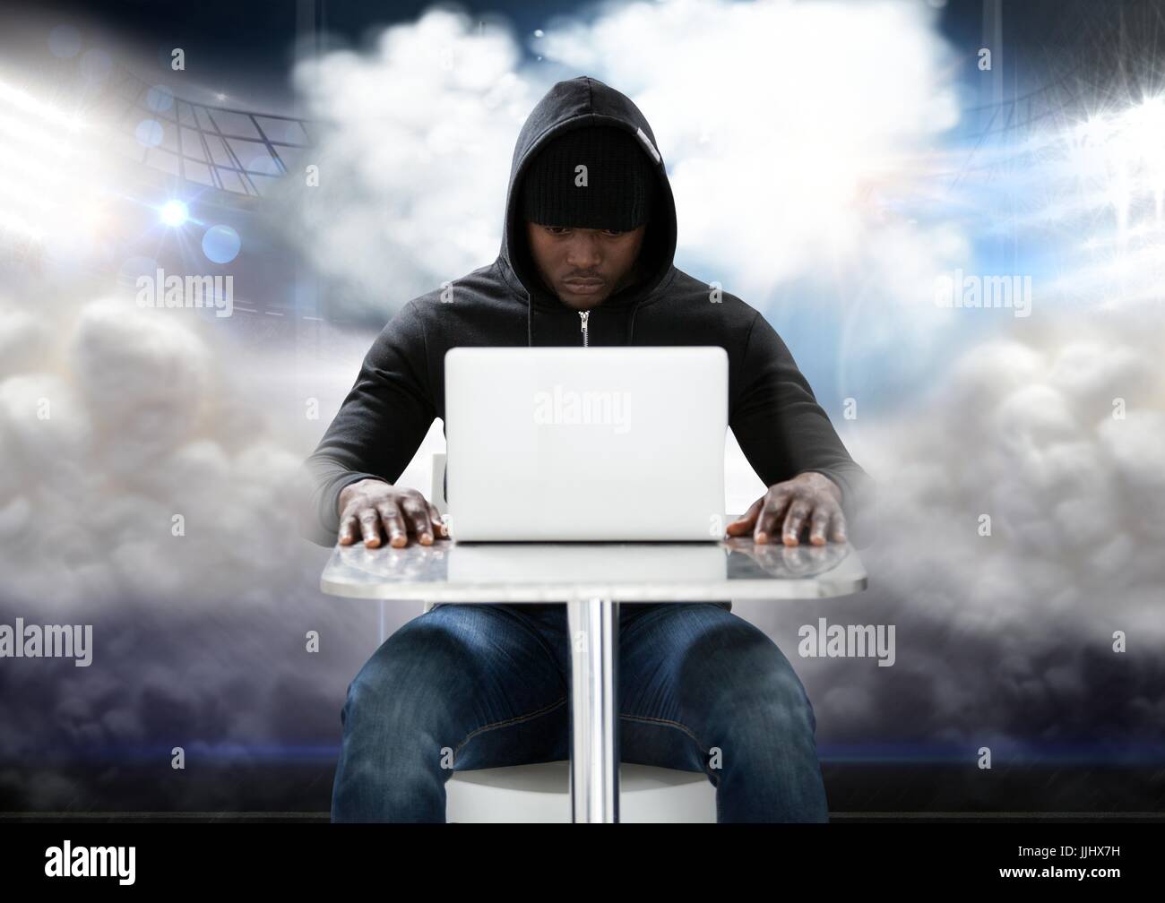 Hacker using a laptop in front of cloudy background Stock Photo - Alamy