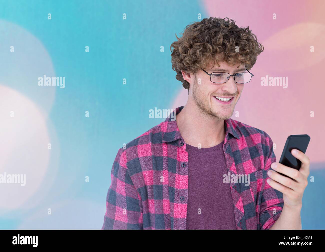 Smiling man texting against colored lights background Stock Photo - Alamy
