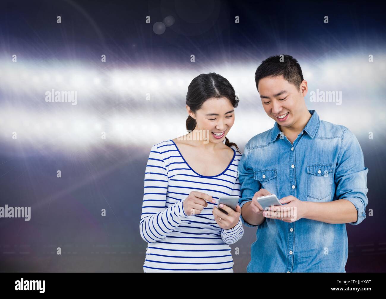 Smiling couple texting against shiny background Stock Photo - Alamy
