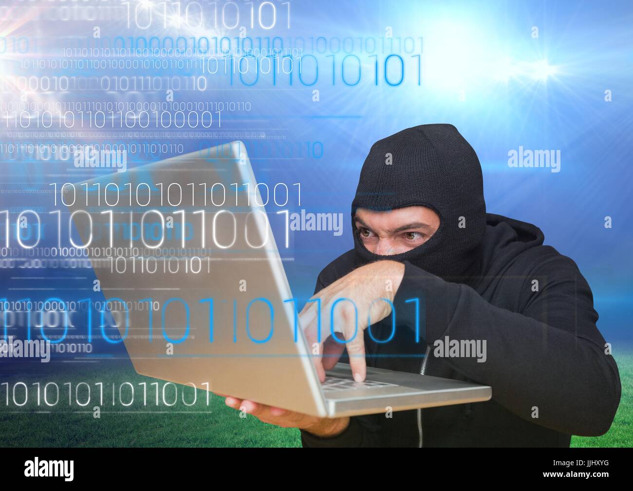 Hacker using a laptop in front of grass field Stock Photo - Alamy