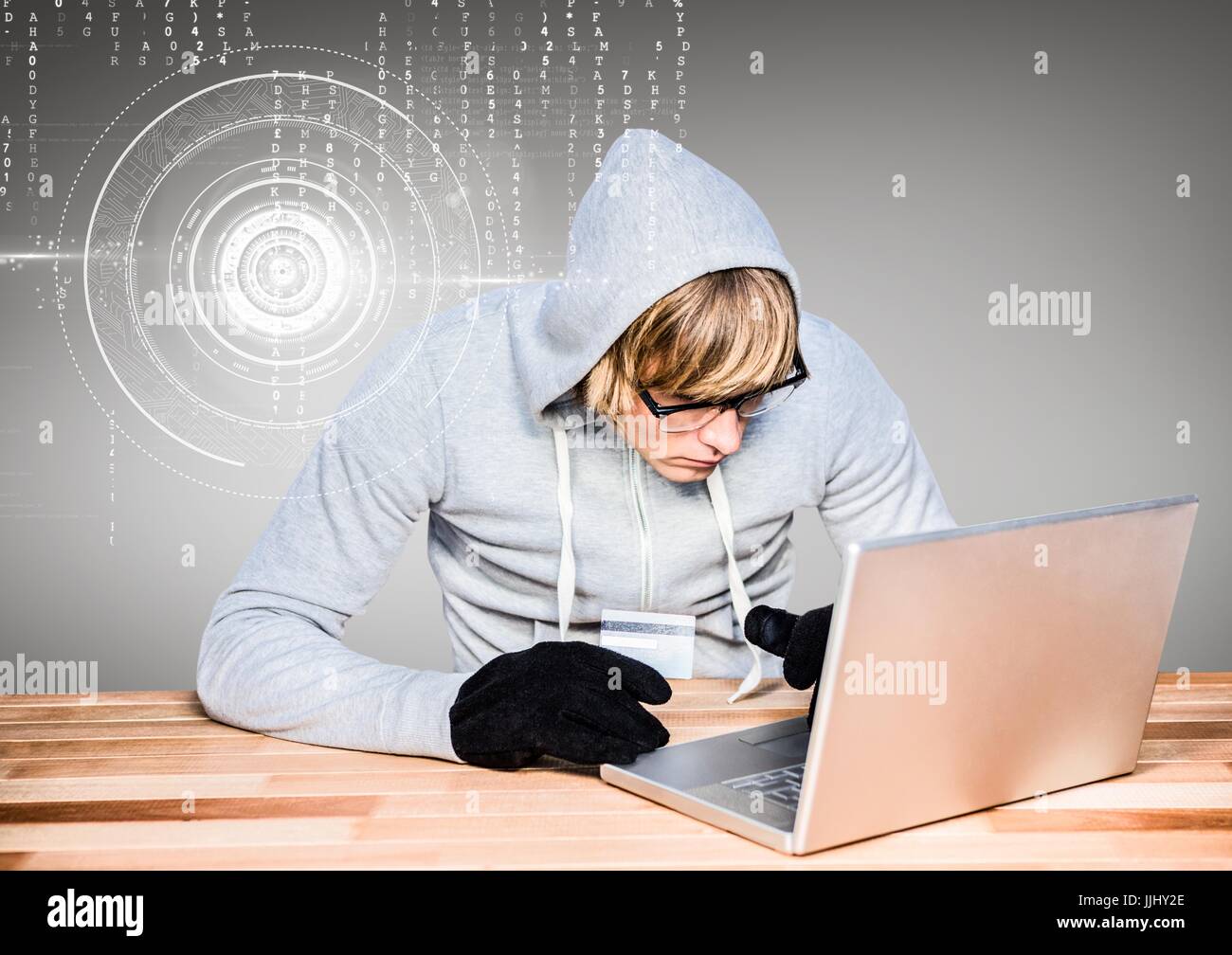Blond-hair hacker using a laptop on wood table in front of grey ...