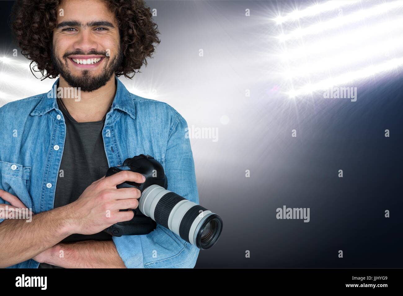 Smiling man with camera on his hands on spotlight background Stock ...