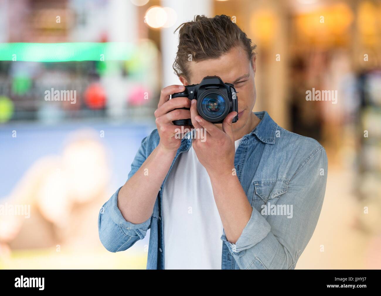 young photographer taking a photo. Store blurred lights background ...