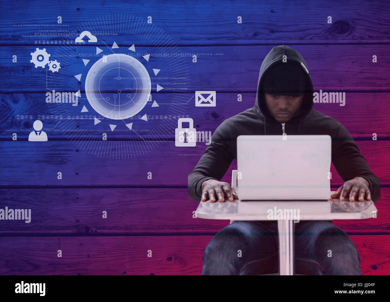 Hacker using a laptop in front of wood background with digital icons ...