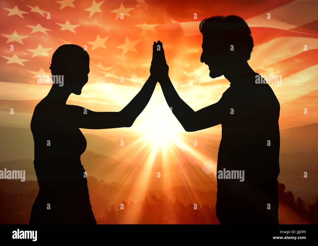 Silhouette of people high fiving against sunset and american flag Stock ...