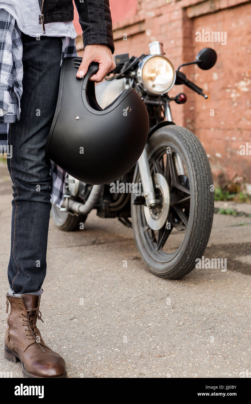 Close-up of a handsome rider biker man hand with black helmet in front ...