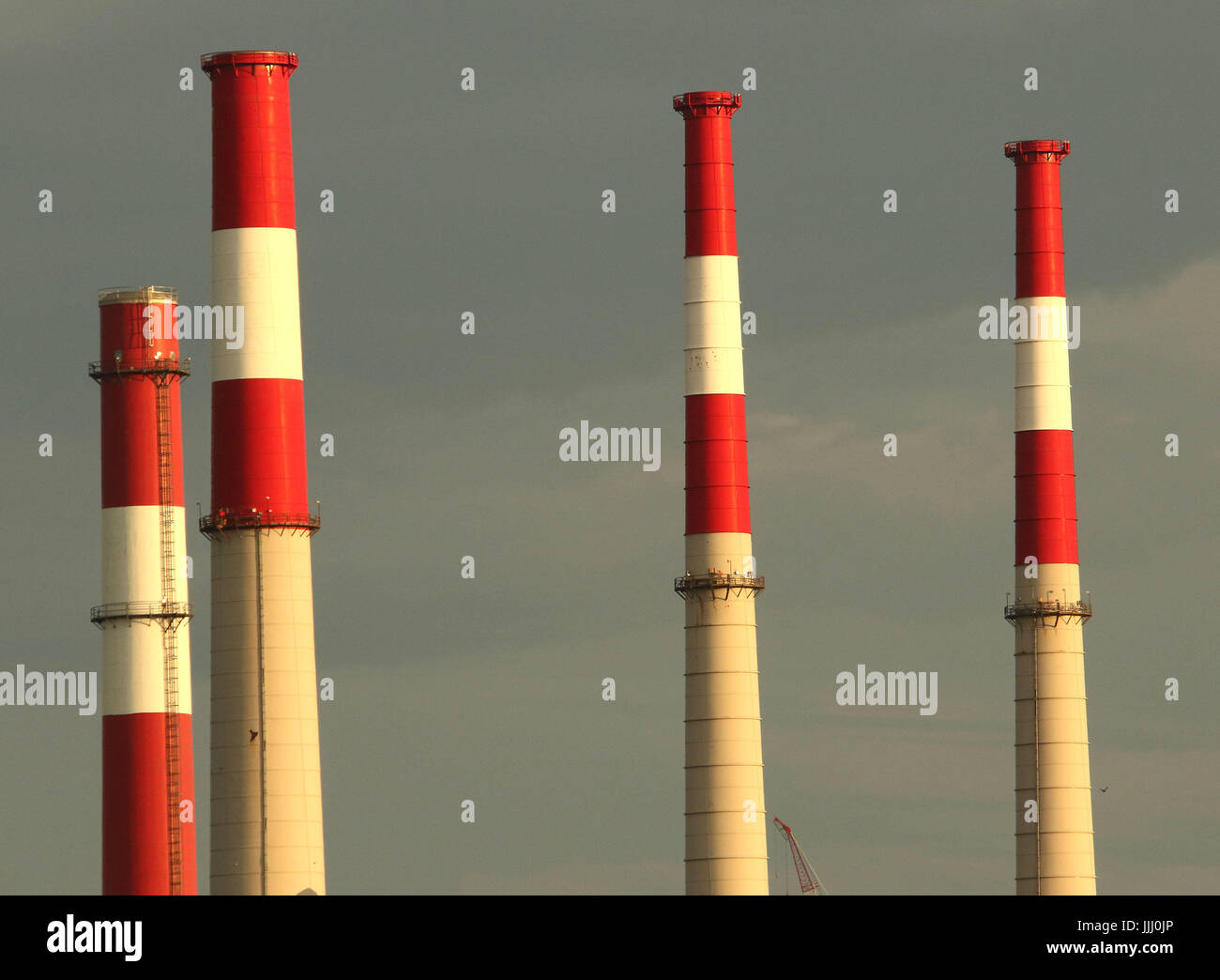 Red and white striped smokestacks seen during sunset Stock Photo - Alamy