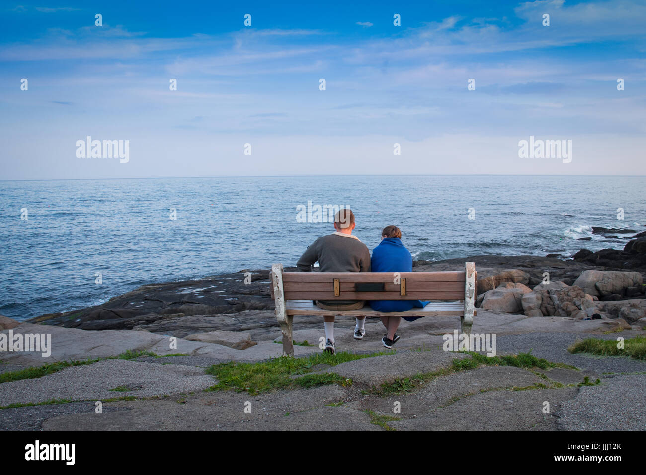 Two lovers peacefully sitting on a bench by the ocean Stock Photo - Alamy