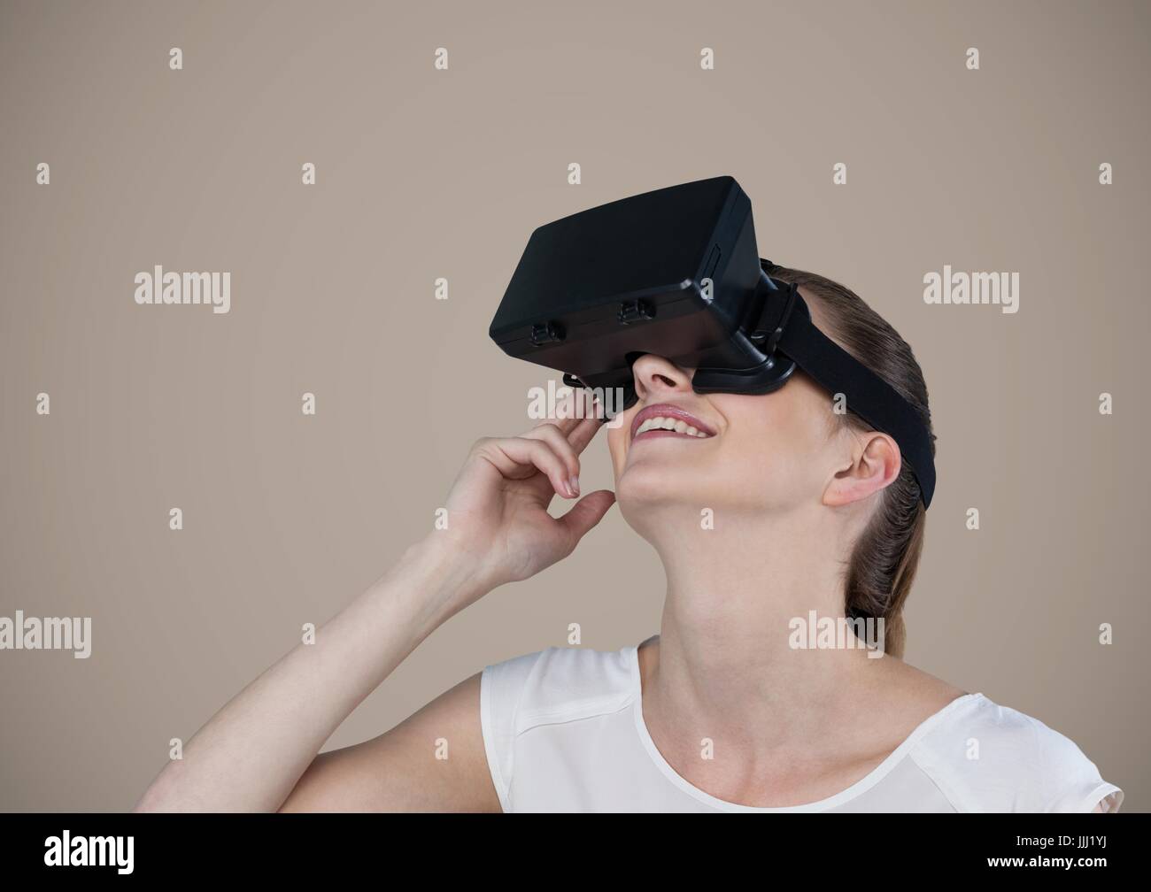 Woman in virtual reality headset against light brown background Stock ...