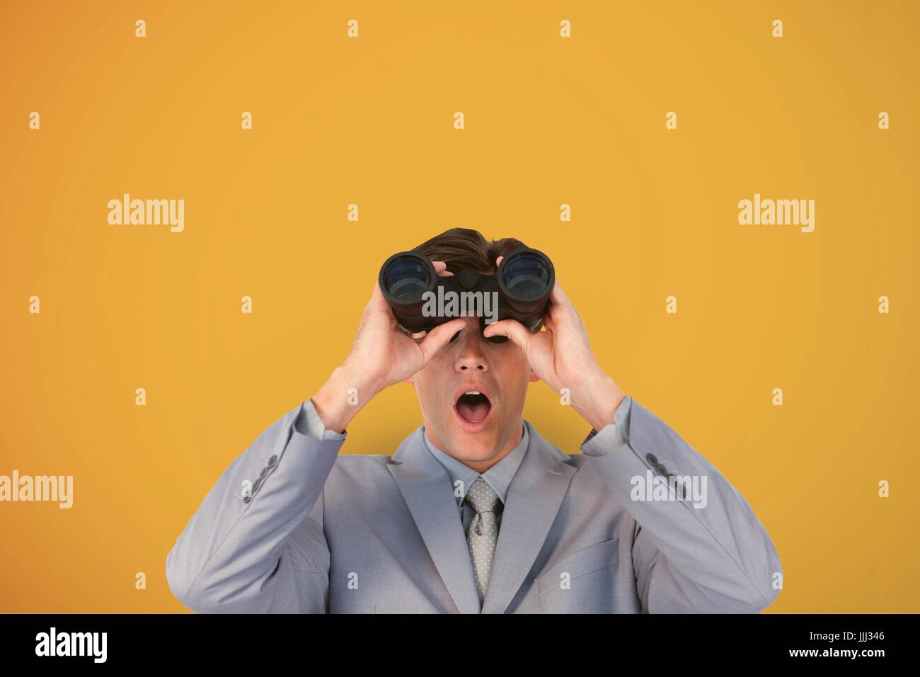 Surprised man looking through binoculars against yellow background ...