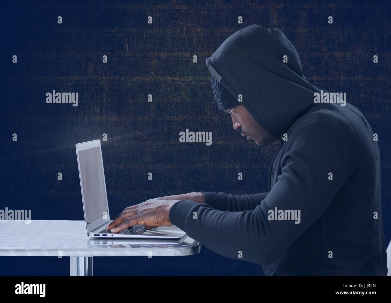 Side view of hacker using a laptop in front of blue background Stock ...