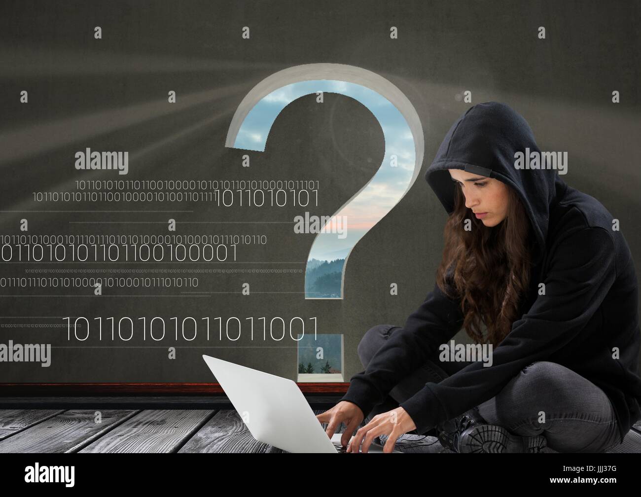 Woman hacker seated and working on a laptop with a grey background with ...
