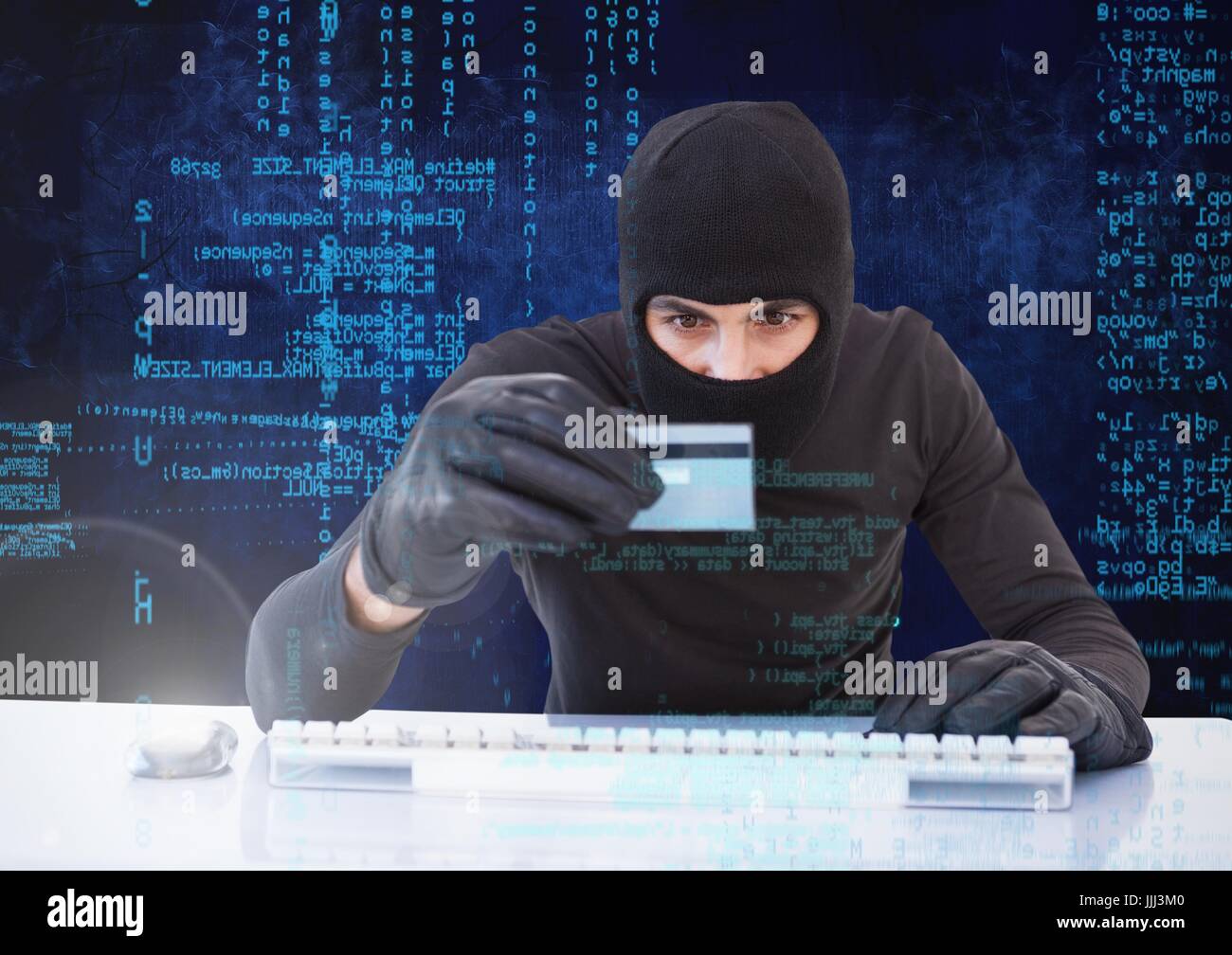 Hacker holding a credit card and typing on a keyboard in front of ...