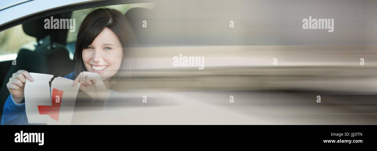 Woman in car with learner L sign ripping with copy space transition ...