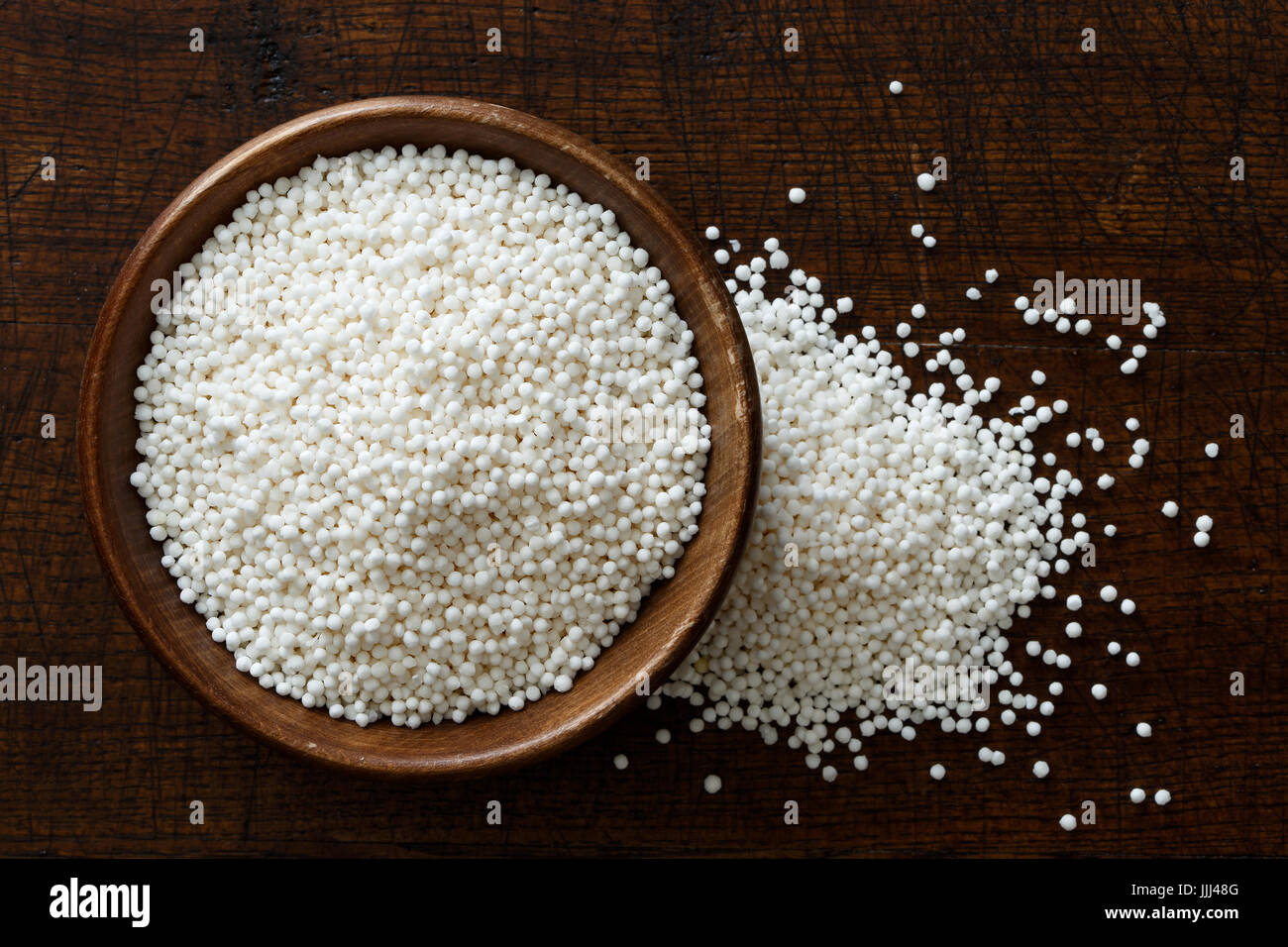Dry tapioca pearls in dark wooden bowl isolated on dark brown wood from ...