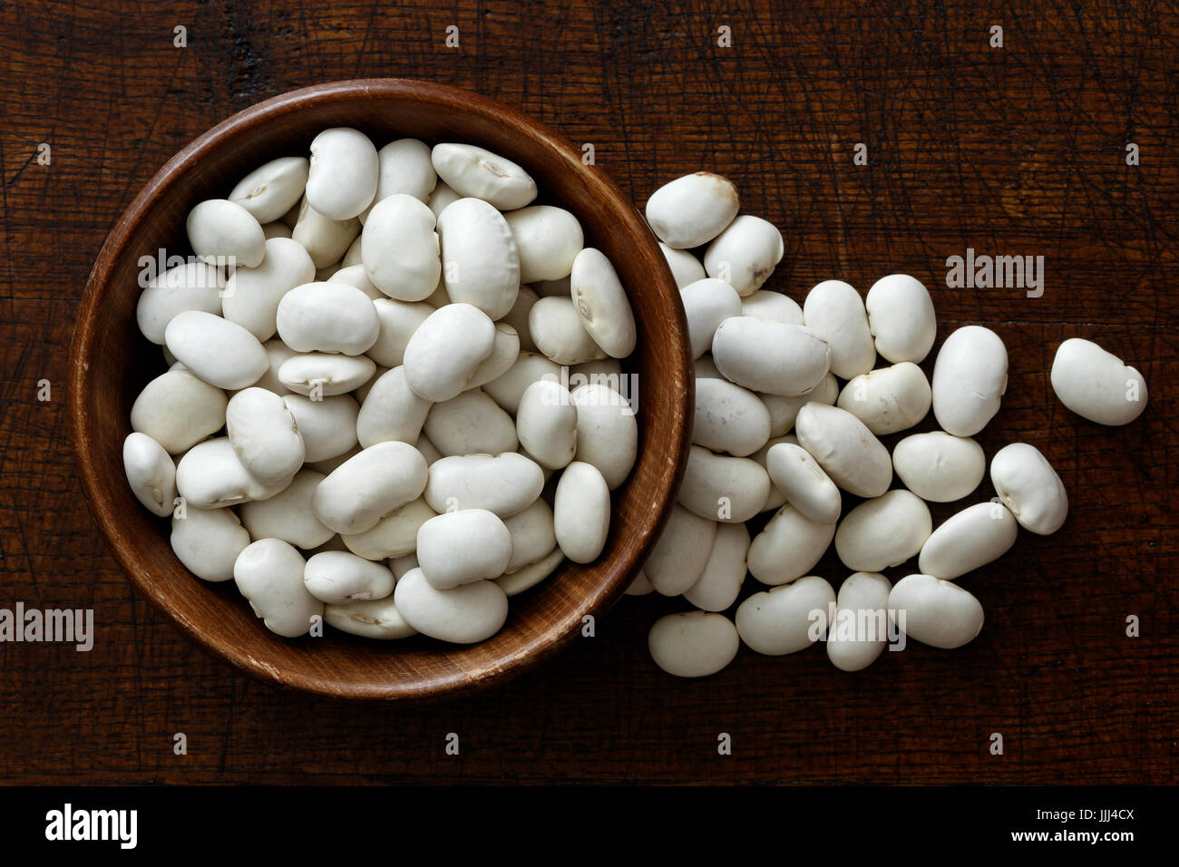 Dry butter beans in dark wooden bowl isolated on dark brown wood from ...