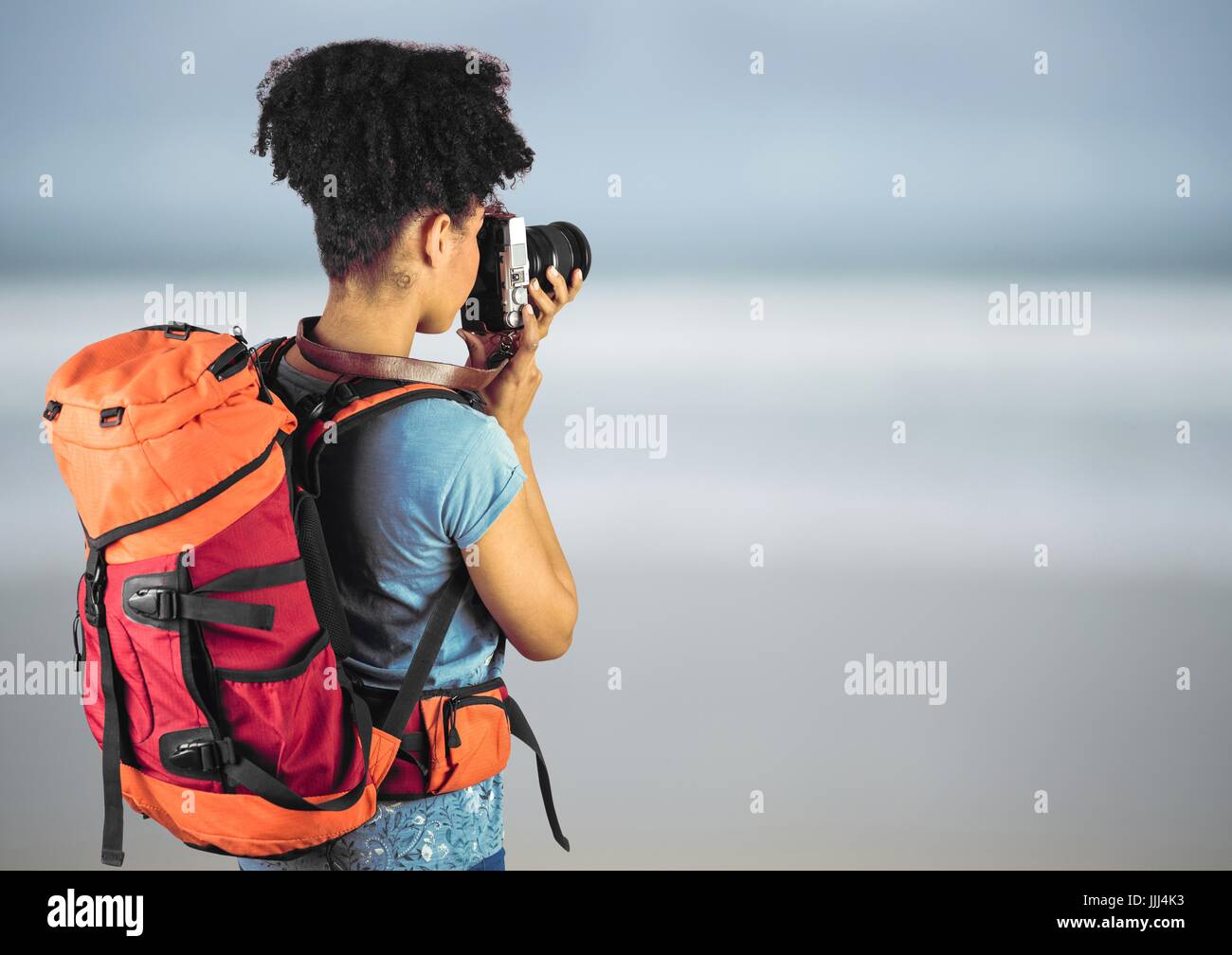Millennial backpacker with camera against blurry beach Stock Photo - Alamy