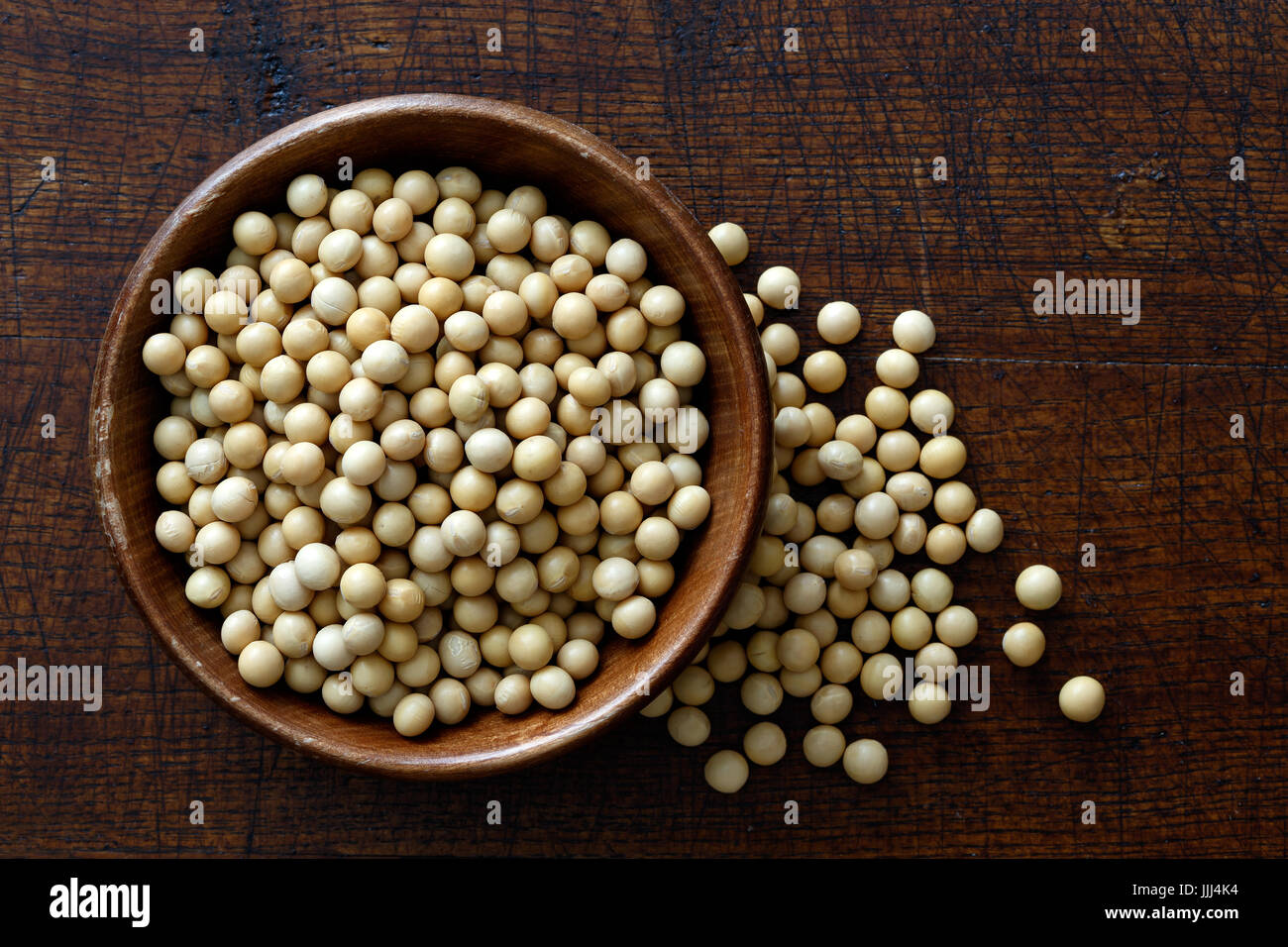 Dry soya beans in dark wooden bowl isolated on dark brown wood from ...