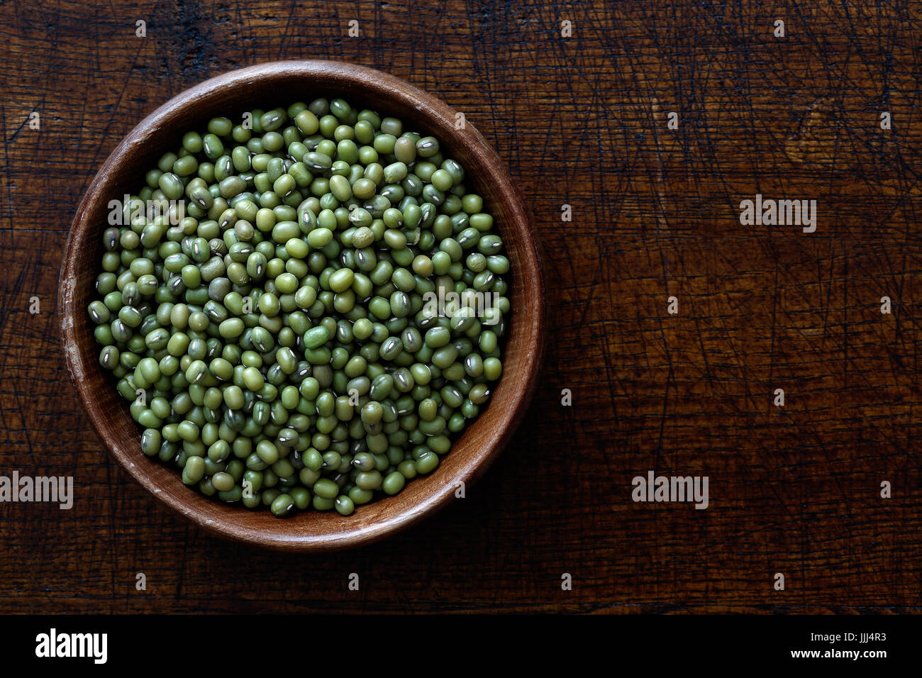 Dry mung beans in dark wooden bowl isolated on dark brown wood from ...