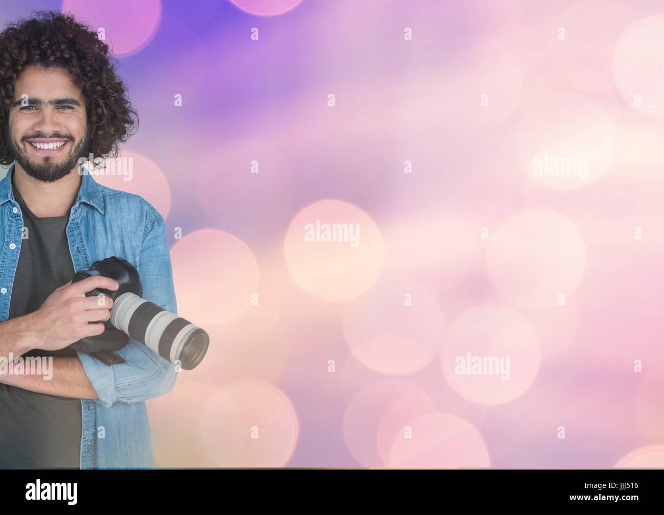 Smiling Photographer holding a camera against glowing background Stock ...