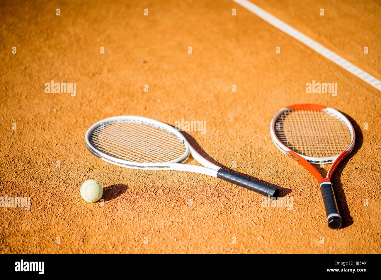 Orange tennis court with rackets and balls outdoors Stock Photo - Alamy