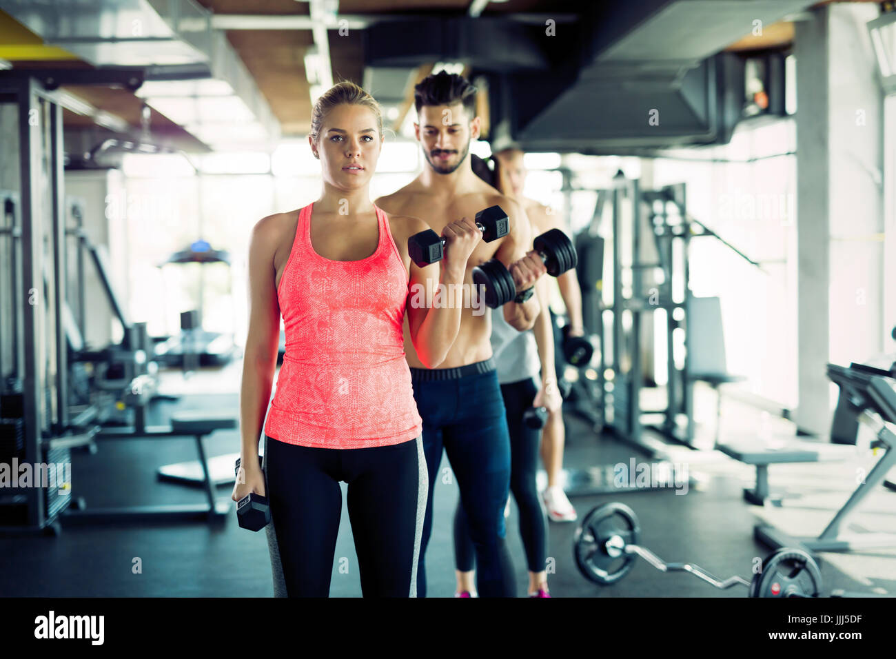 Personal trainer helping young woman with exercises for biceps Stock ...