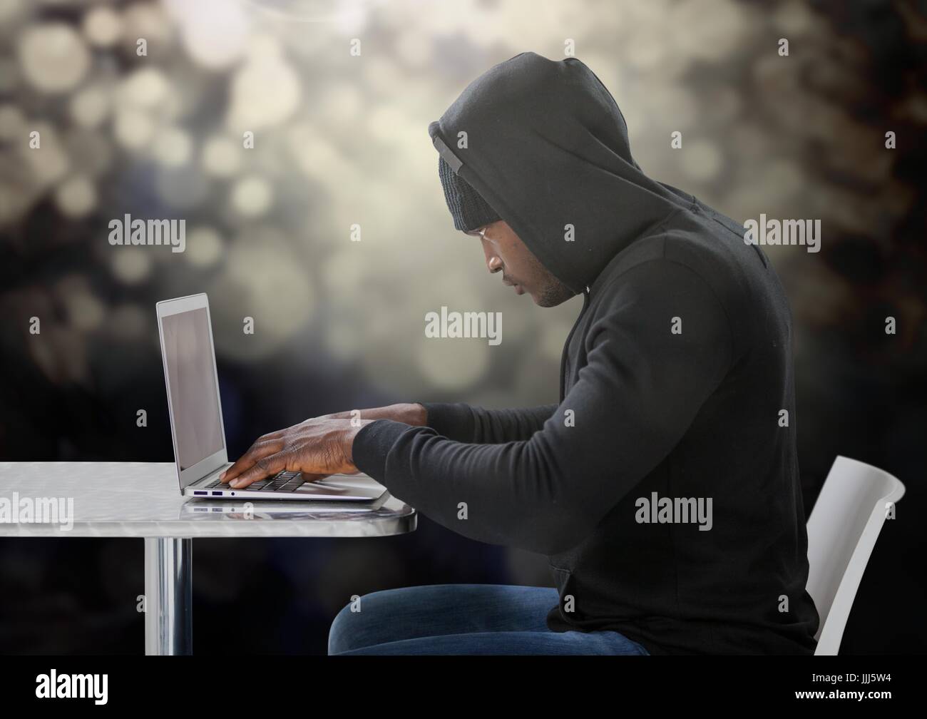 Side view of hacker using a laptop on a table Stock Photo - Alamy