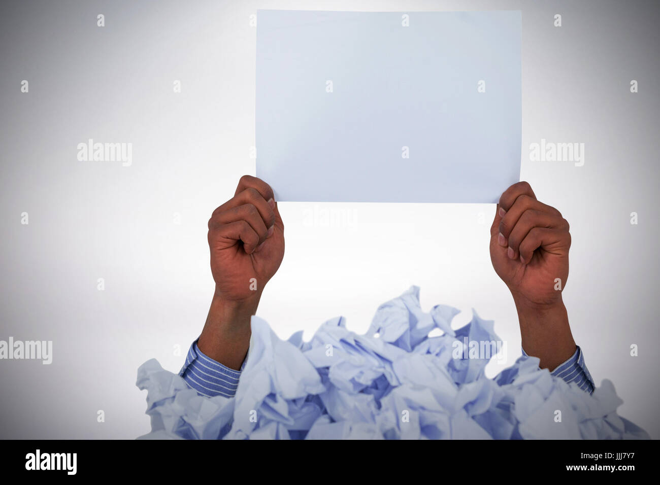 Composite image of heap of crumpled paper with hand holding blank page ...