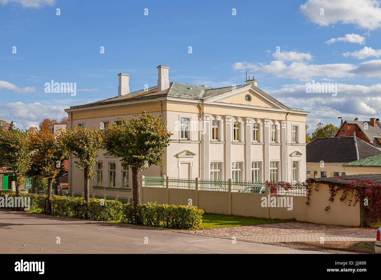 Pretty town view with shaped trees and bushes and yellow stone building ...