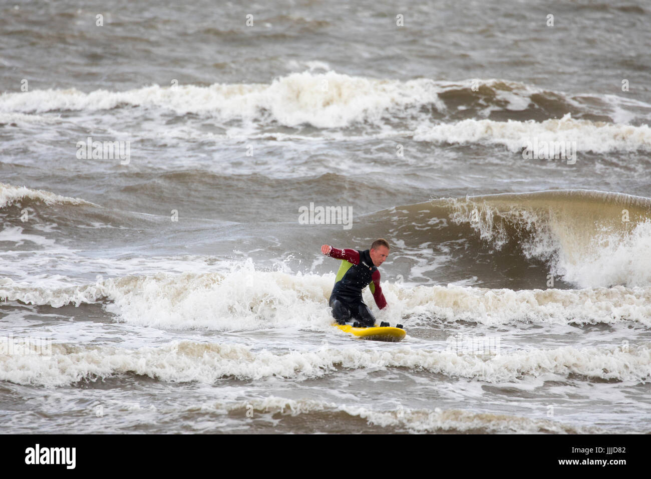 A male RNLI lifeguard coming to shore on a rescue board having ...