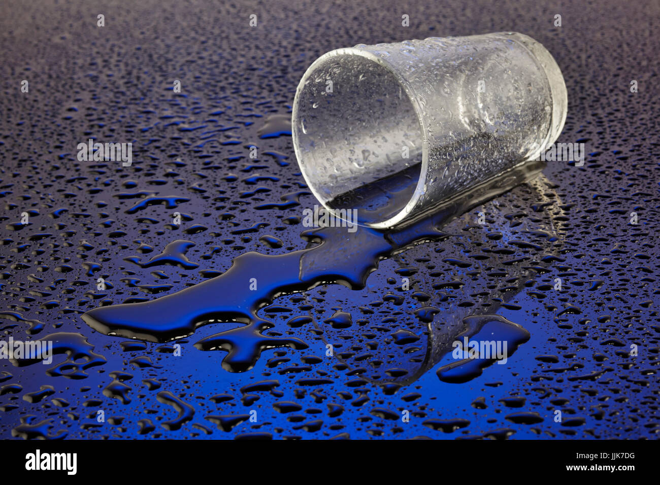 Glass of water spilled with drops on light background Stock Photo - Alamy